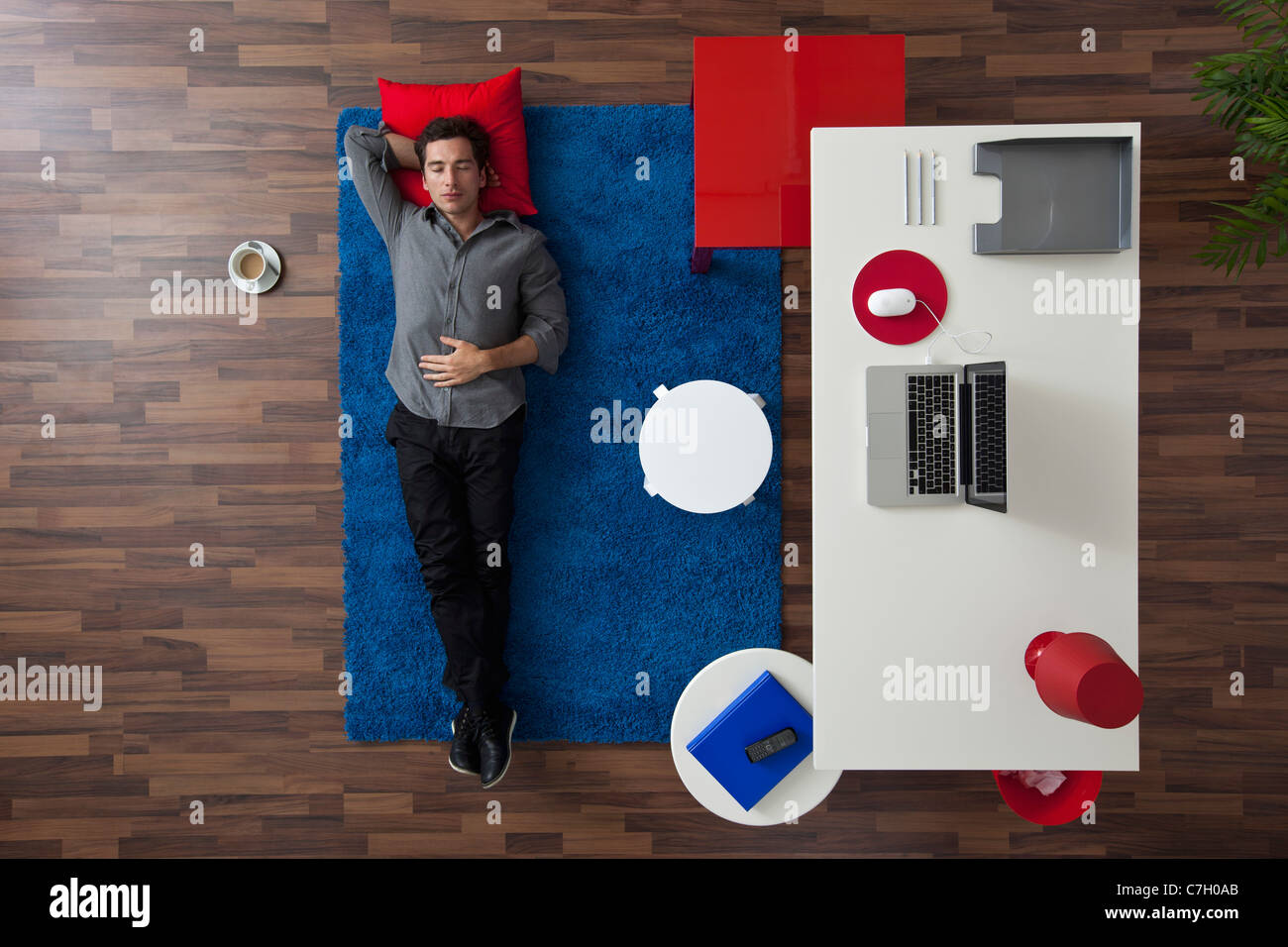 A man lying on a rug next to his home office desk, overhead view Stock ...