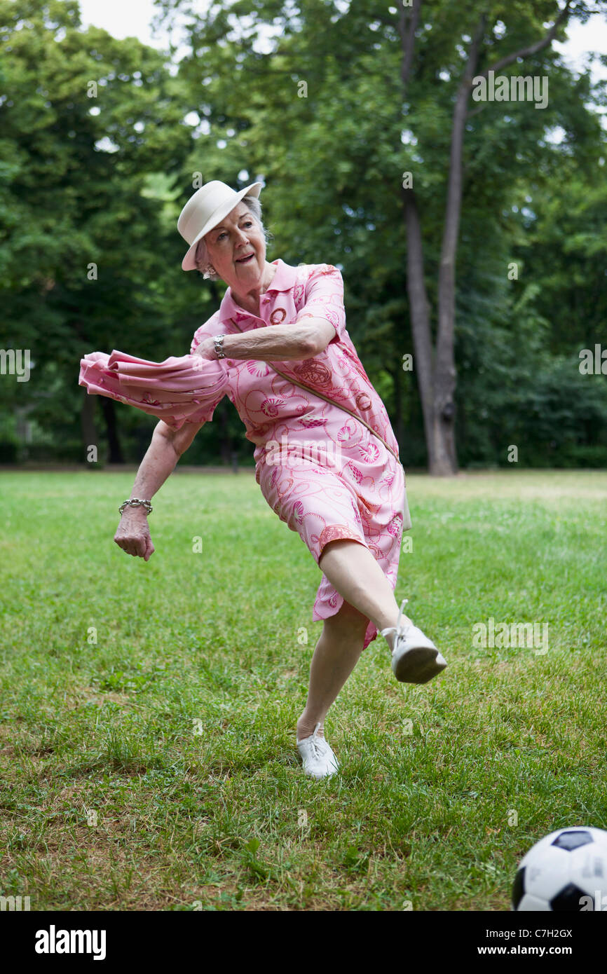 Senior woman kicks football n the park Stock Photo - Alamy