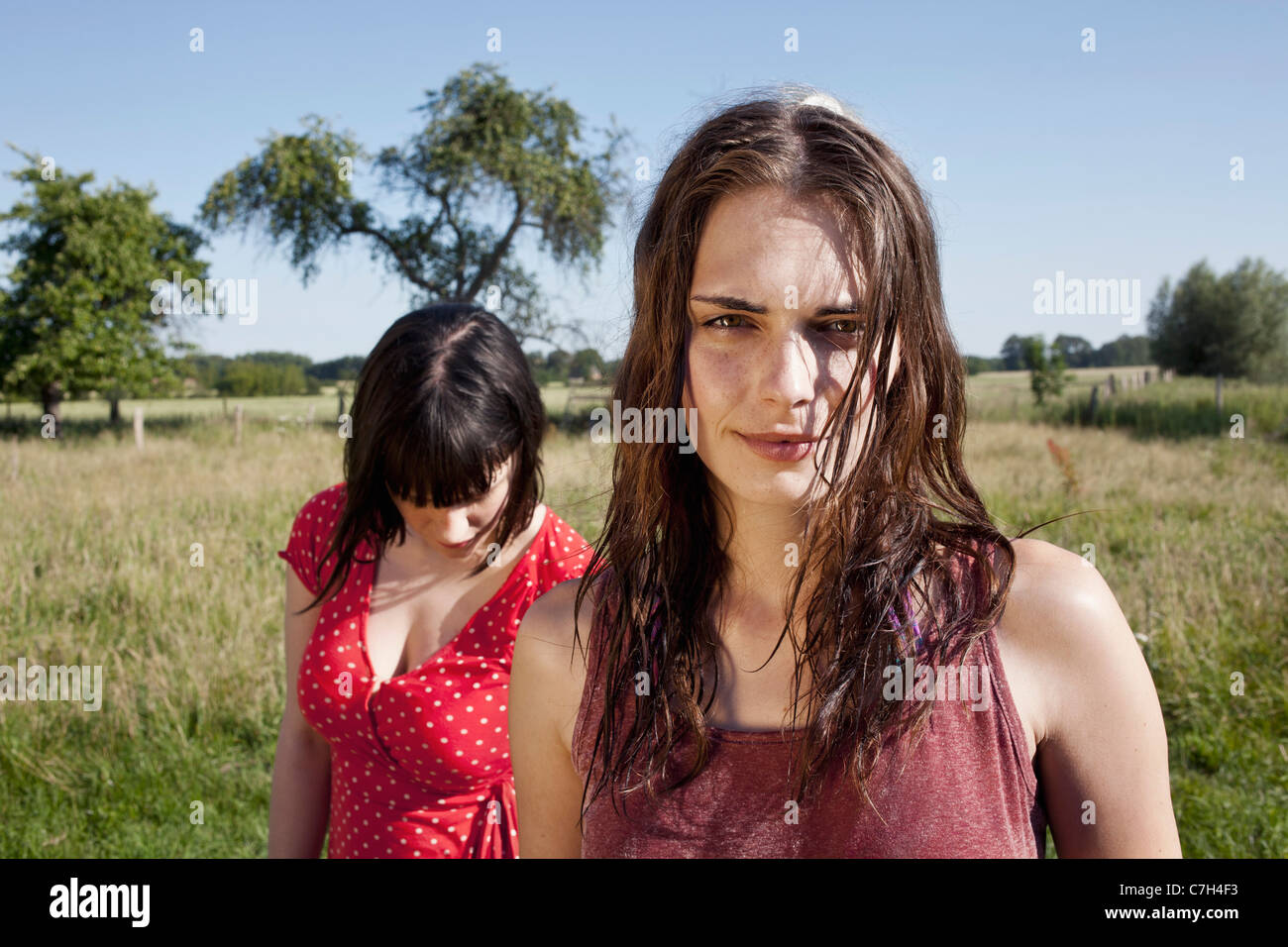 Two cool girls standing in field with one looking at camera Stock Photo ...