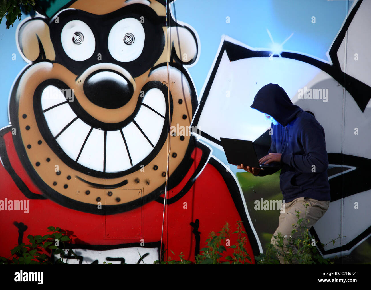 Computer user, hacker, sits conspiratorially with a laptop, in front of ...