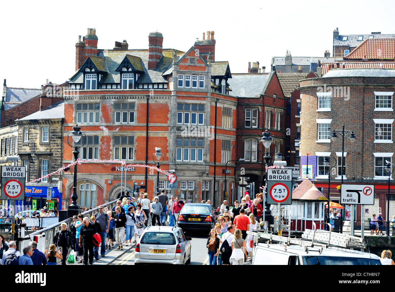 A busy street scene of people crossing the Whitby swing bridge, England ...