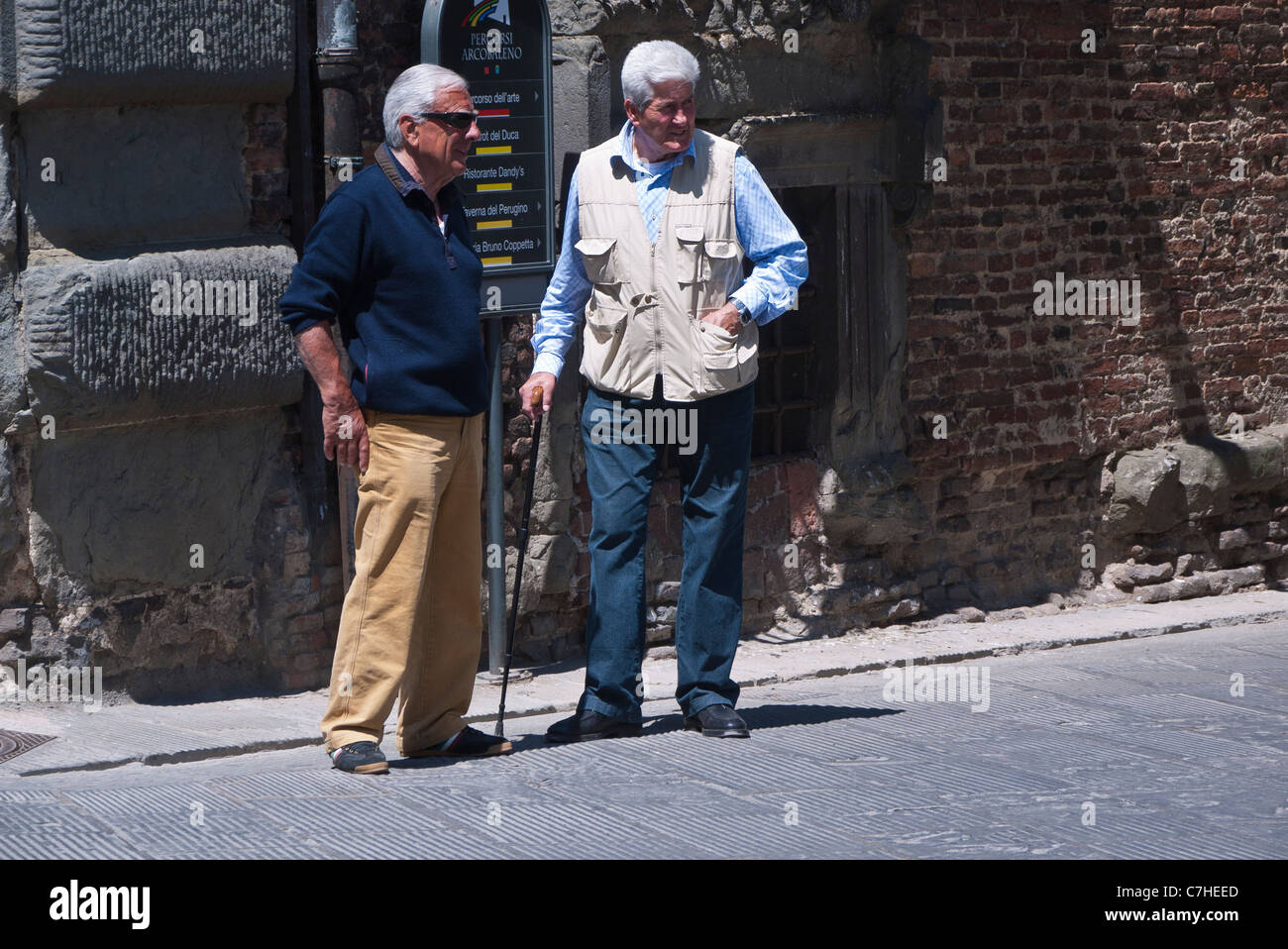 Two Italian male senior citizens stand and talk on street corner in ...