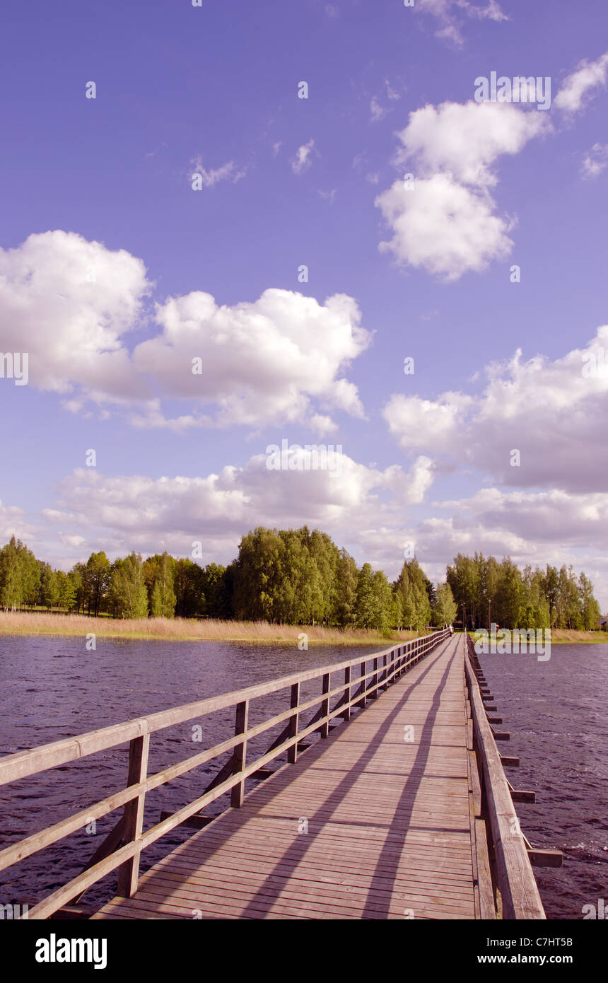 Long wooden footbridge with handrails over the lake and the man walking ...