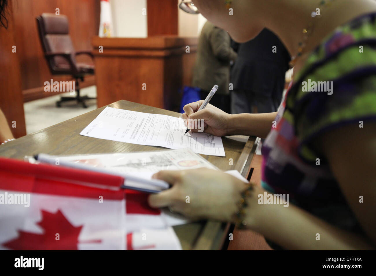 Young woman signing documents accepting Canadian citizenship in in a ...