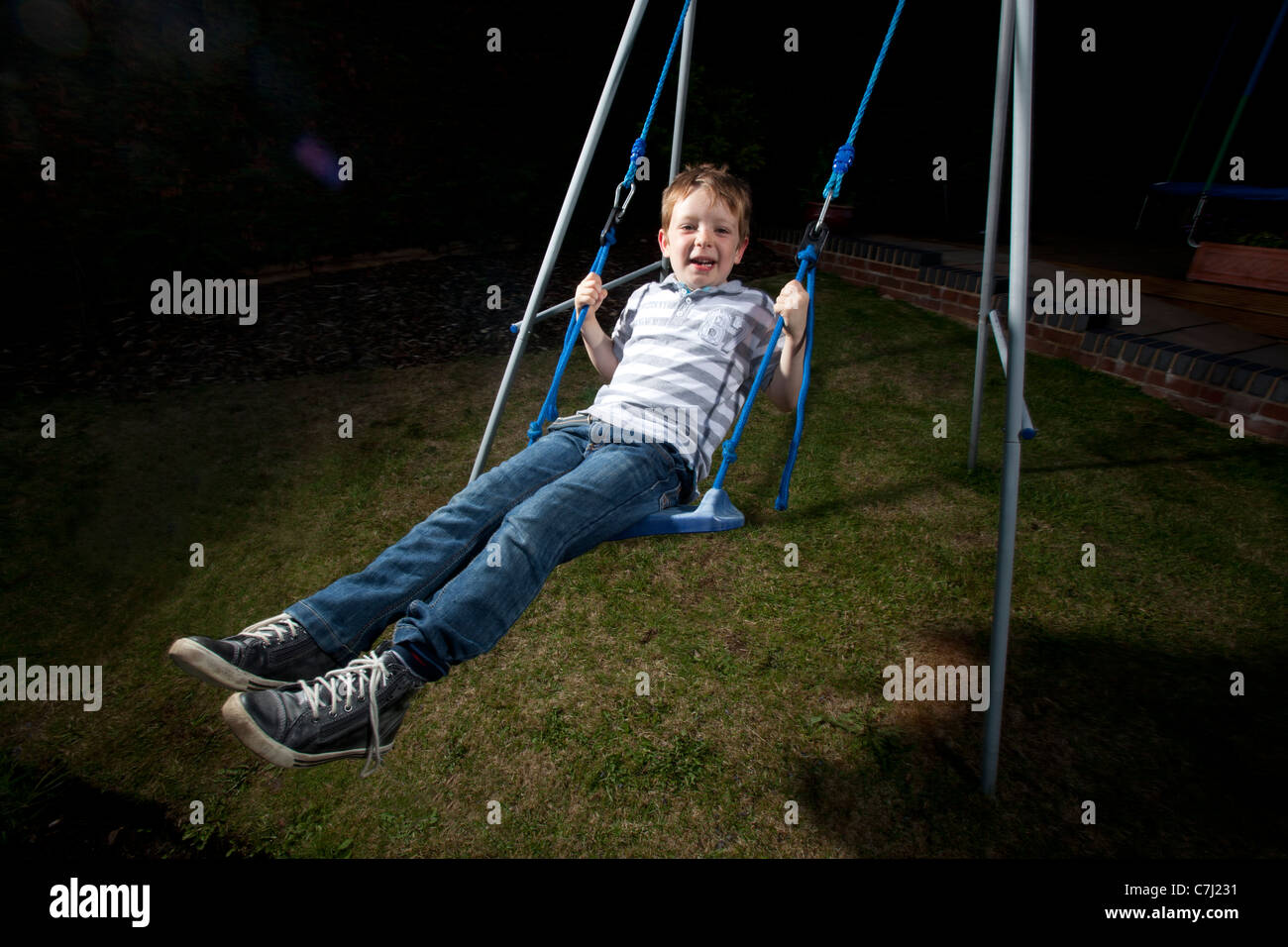A young boy playing on a garden swing Stock Photo - Alamy