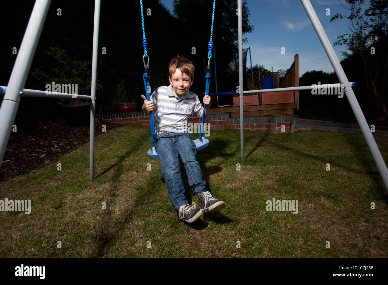 A young boy playing on a garden swing Stock Photo - Alamy