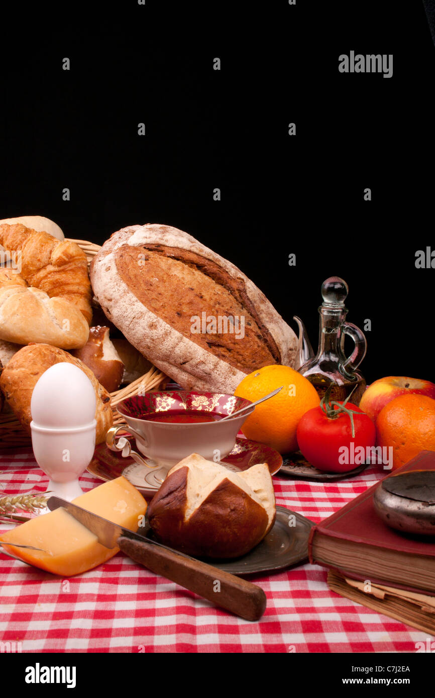 Old fashioned lunch with bread and buns on a table against a black ...