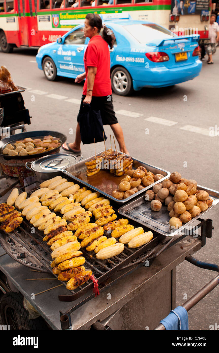 Woman walking in a street market in Bangkok, stall selling Thai hot ...