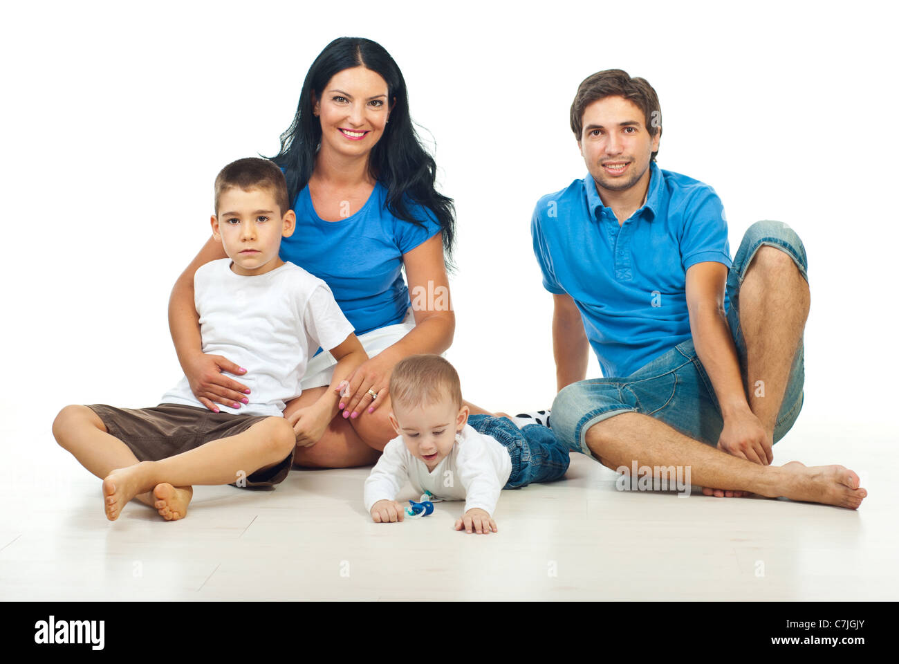 Happy family with two sons sitting on floor in their home against white ...