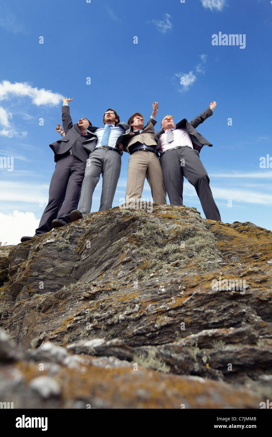 Businessmen cheering on cliff Stock Photo - Alamy