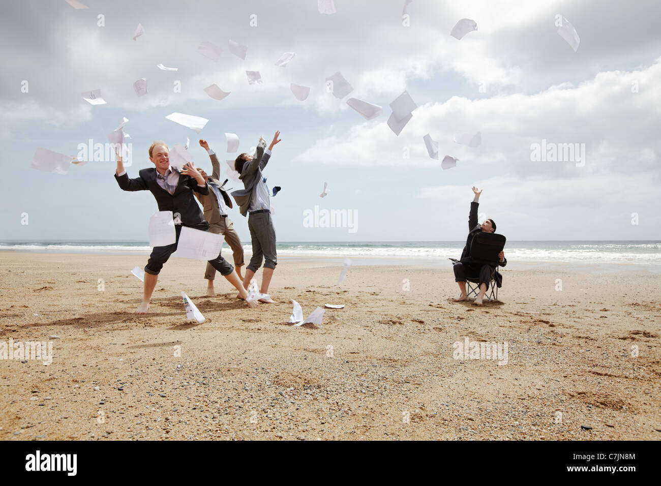 Businessmen tossing papers away at beach Stock Photo - Alamy