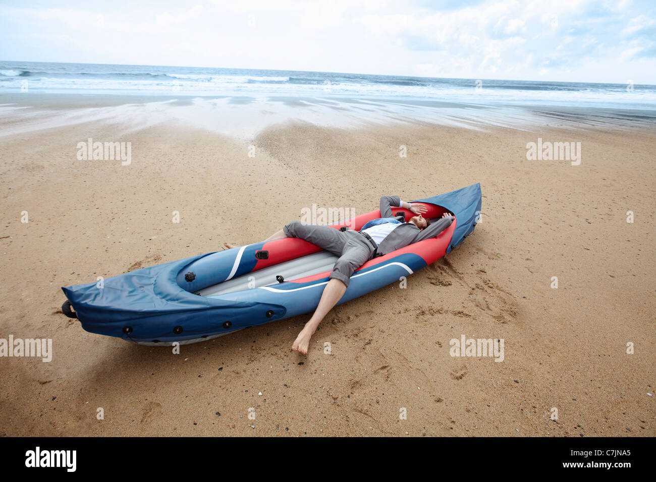 Businessmen laying in canoe on beach Stock Photo - Alamy
