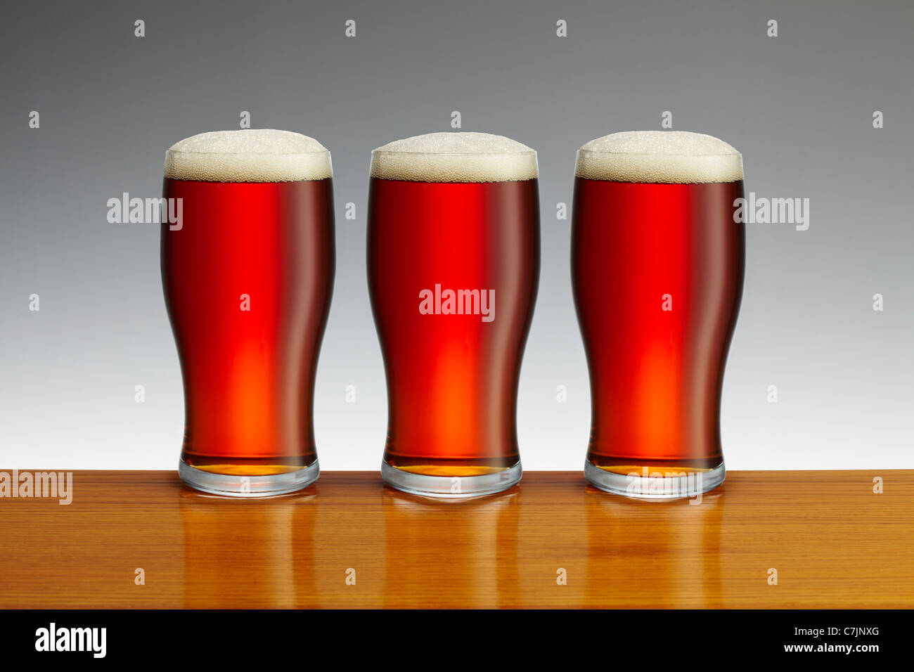 Three Pints of Beer on wooden bar top Stock Photo - Alamy