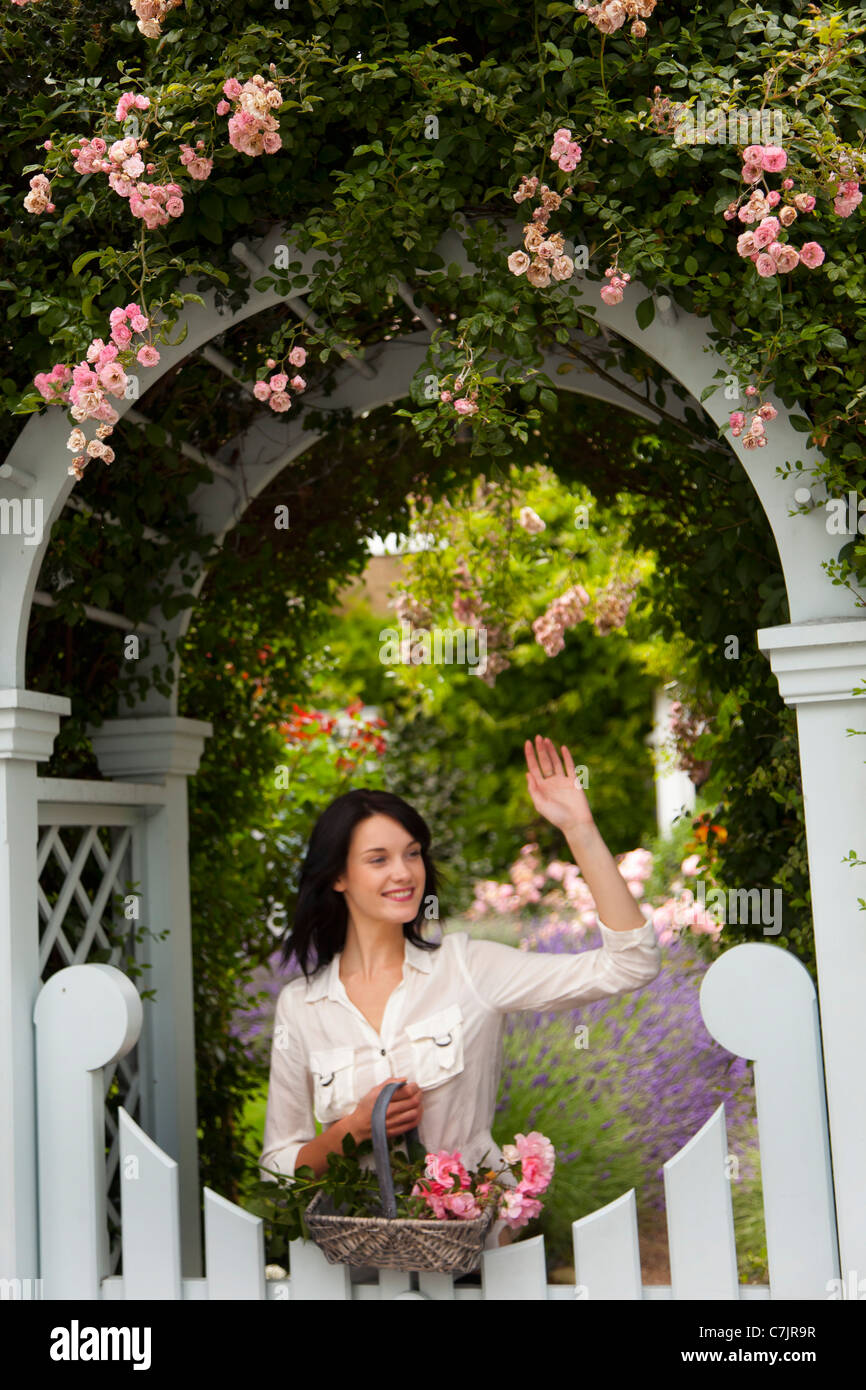 Woman with flowers waving from gate Stock Photo - Alamy