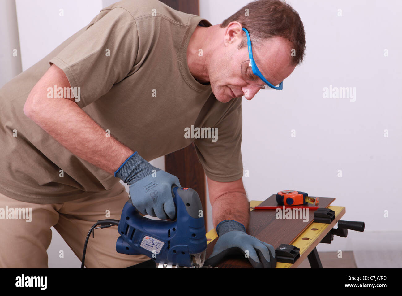 Man using an electric saw to cut a wooden floorboard Stock Photo - Alamy