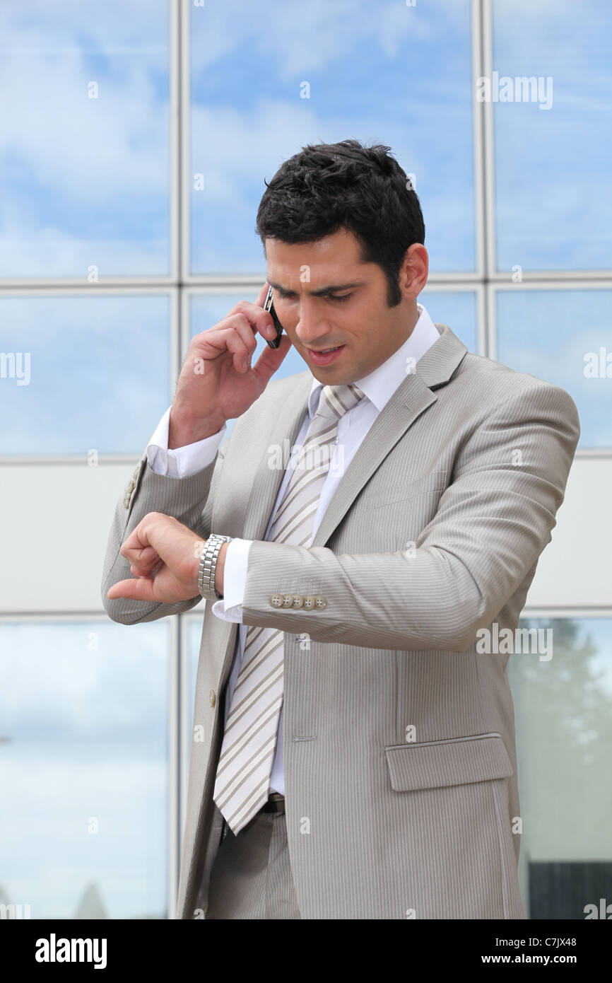 Businessman cell phone checking watch hi-res stock photography and ...