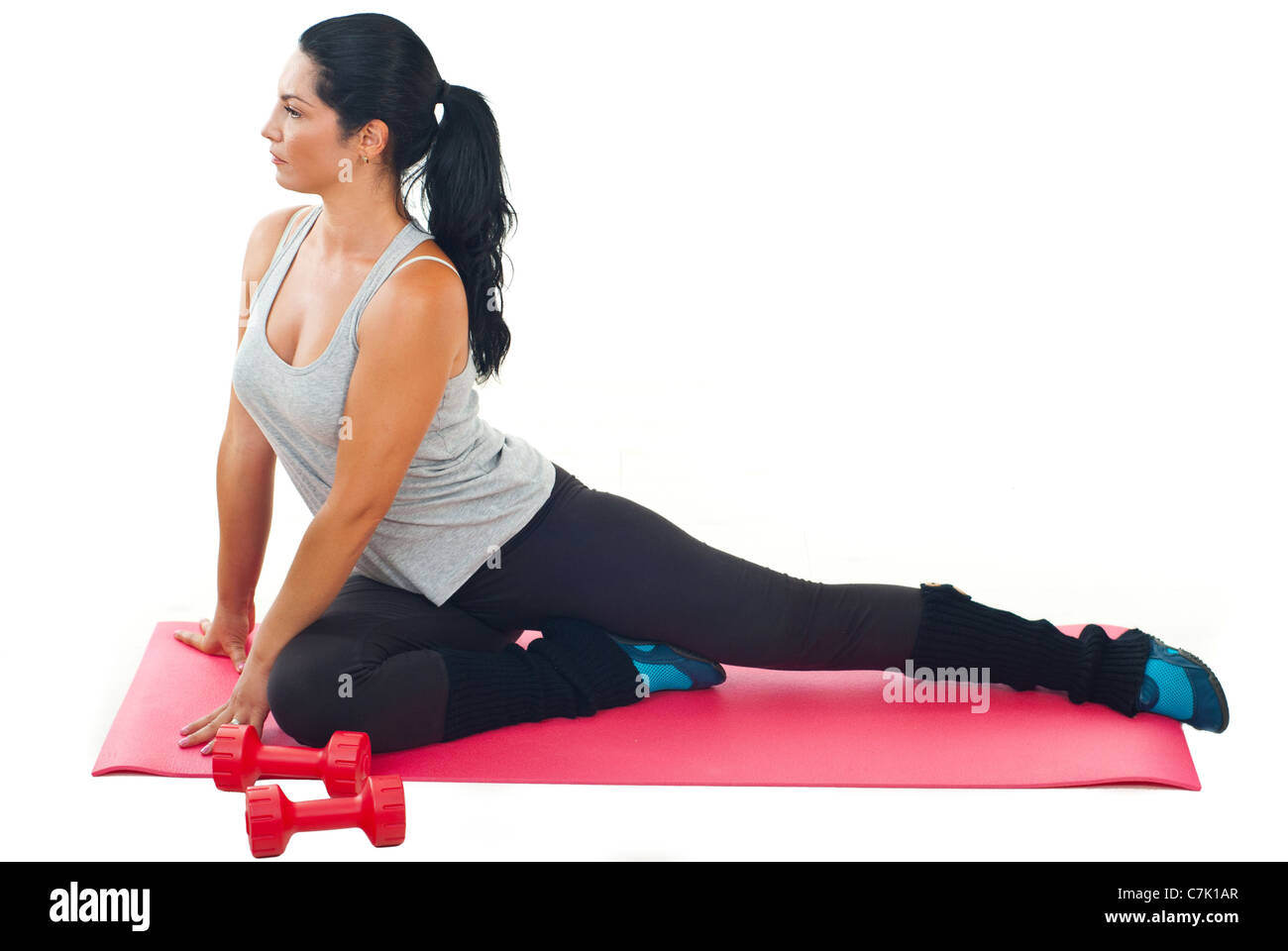 Fitness woman sitting on red mat and stretch her body isolated on white ...