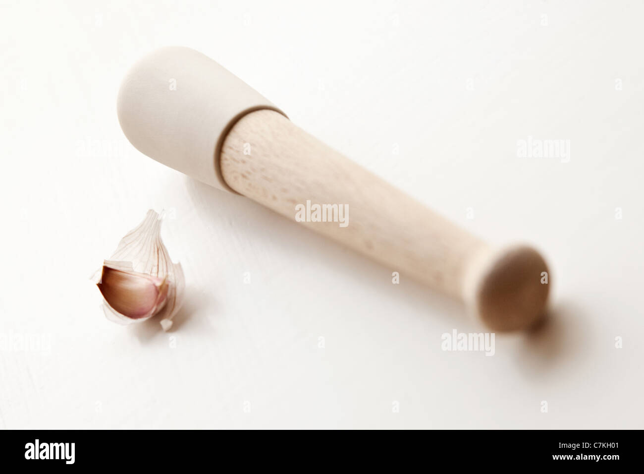 A mortar and pestle with a clove of garlic against a white background ...