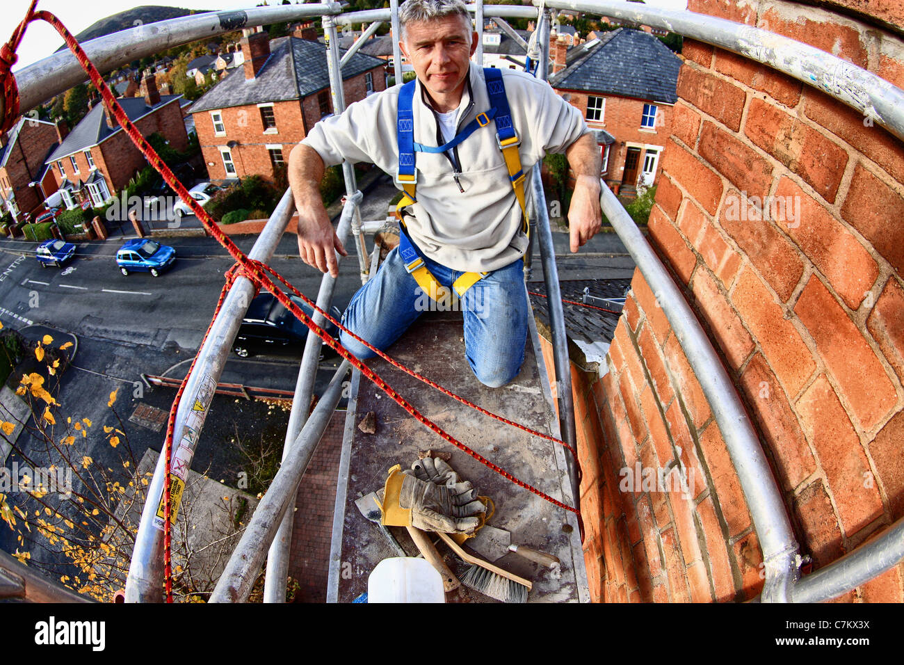 man on scaffold tower up the side of a house wearing safety harness ...