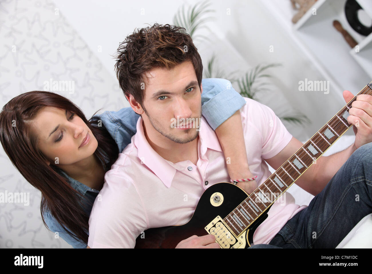 Woman hugging her boyfriend while he plays the guitar Stock Photo - Alamy