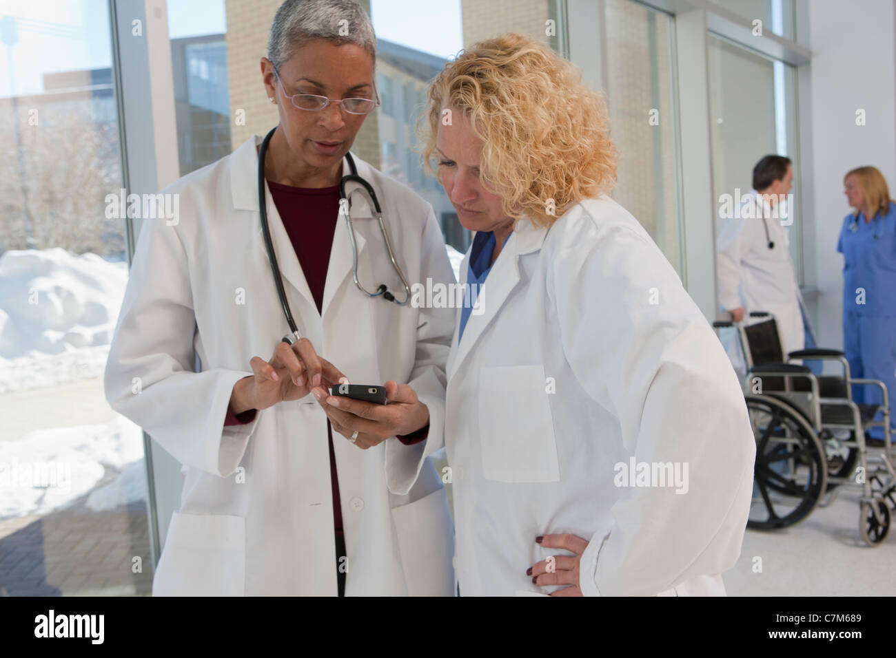 Two female doctors reading text message on a mobile phone with their ...