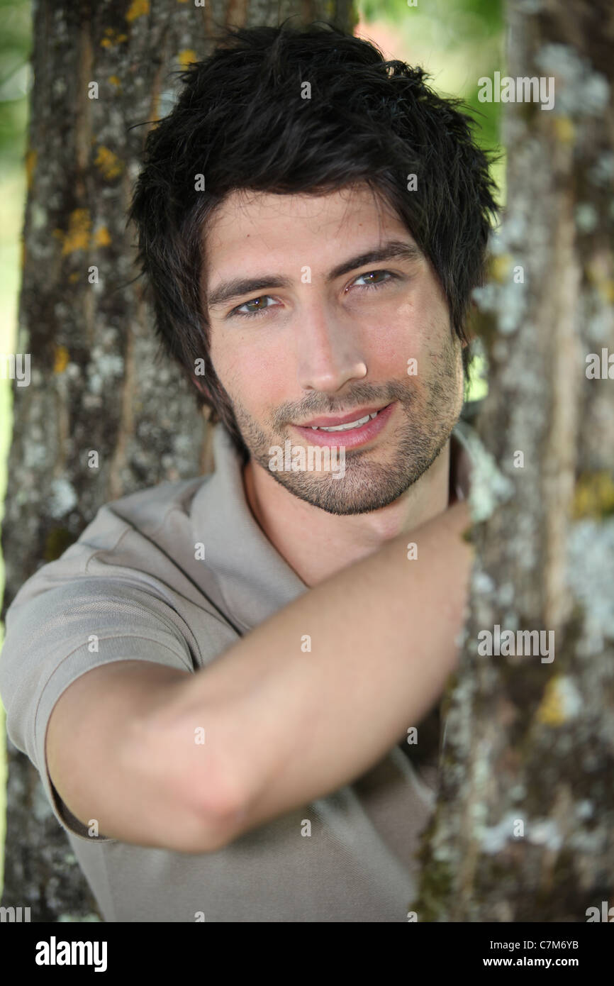 Man stood against tree Stock Photo - Alamy