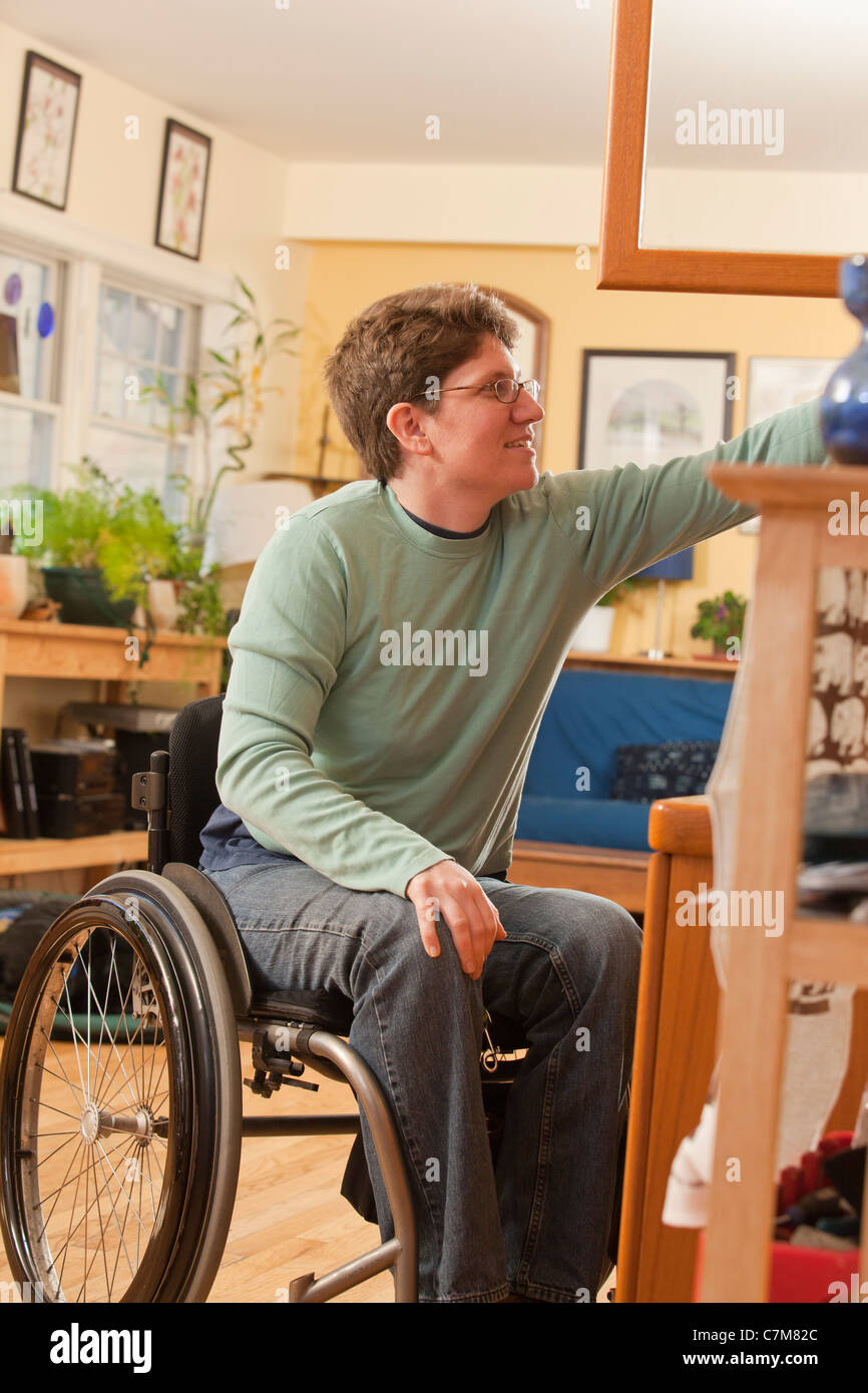 Woman with multiple sclerosis in a wheelchair getting table settings ...