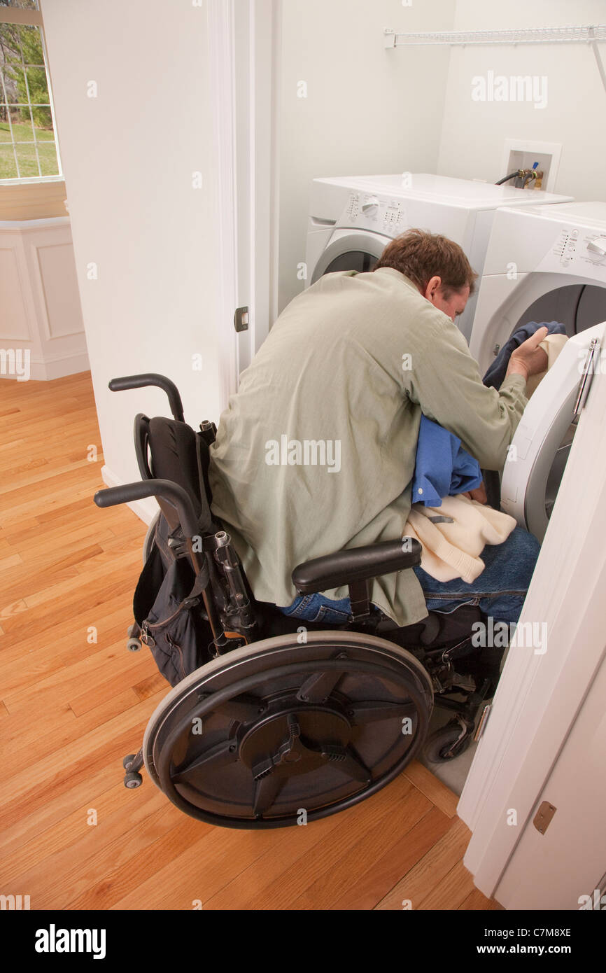 Man with spinal cord injury in a wheelchair doing his laundry at home ...