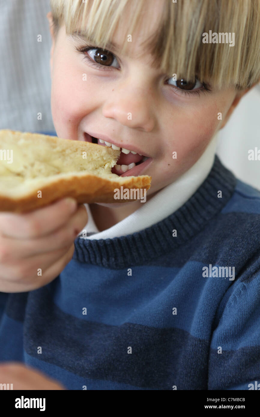 little blond boy eating slice of bread and butter Stock Photo - Alamy