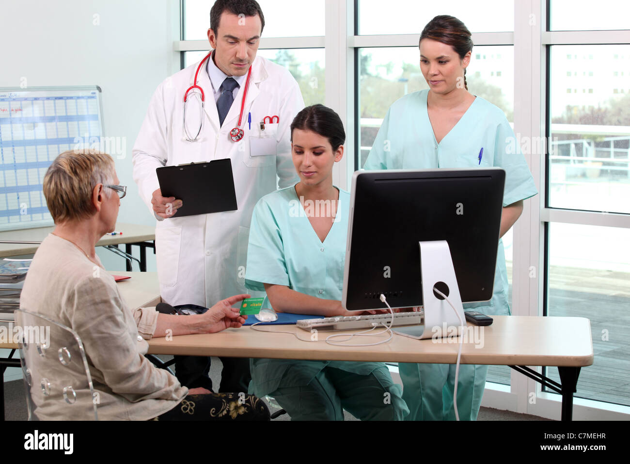 Doctor, patient, and medical secretaries at reception Stock Photo - Alamy