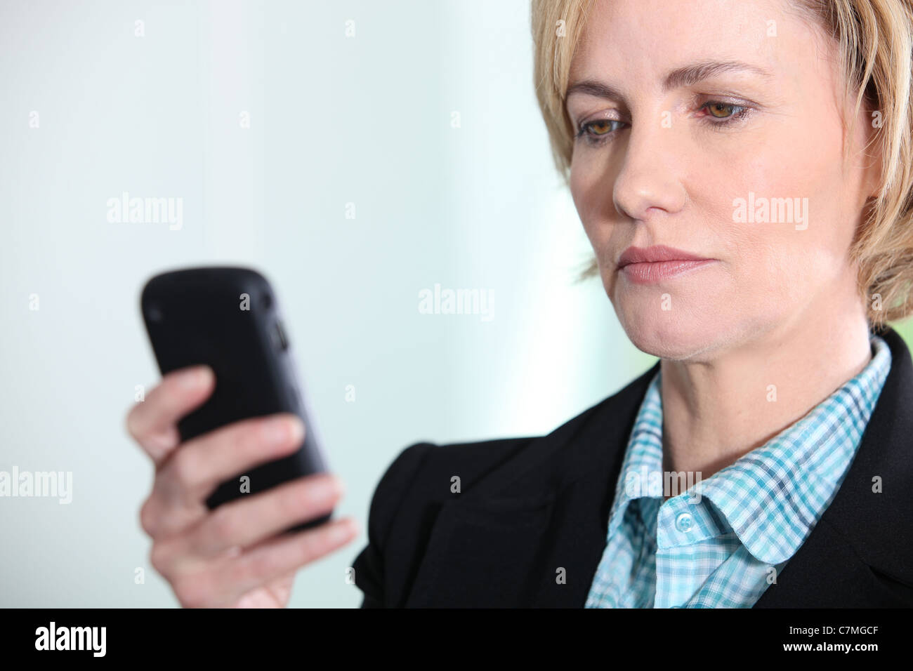 Blond woman looking at mobile telephone screen Stock Photo - Alamy