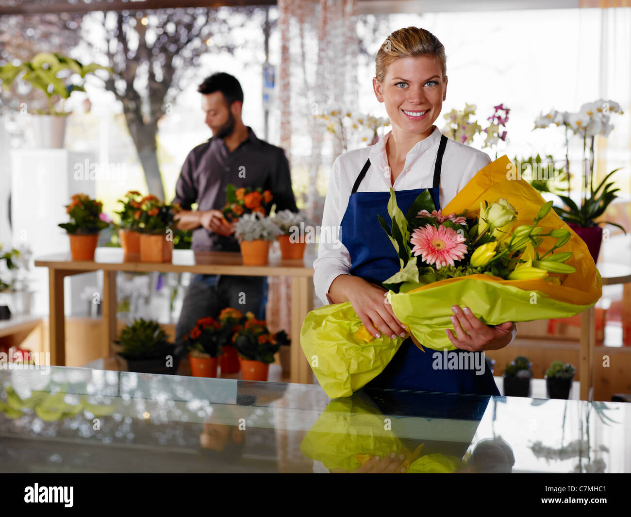 Female sales assistant working as florist and holding bouquet with ...