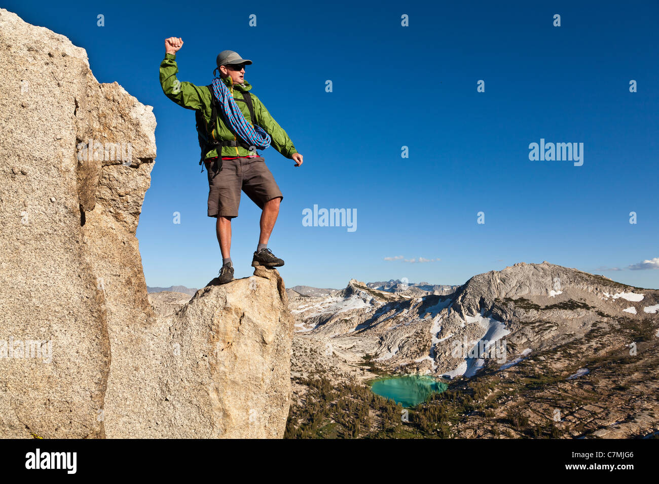 Male rock climber celebrates on the summit after a successful ascent ...