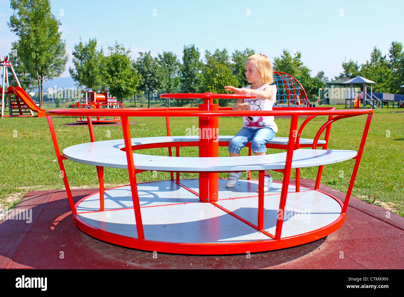Little girl playing on the merry-go-round in playground Stock Photo - Alamy