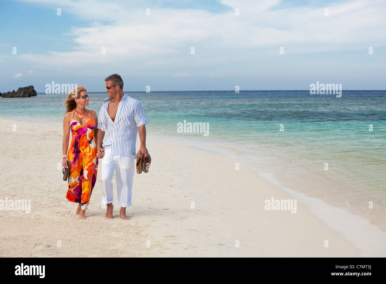 Couple walking hand-in-hand along tropical beach Stock Photo - Alamy