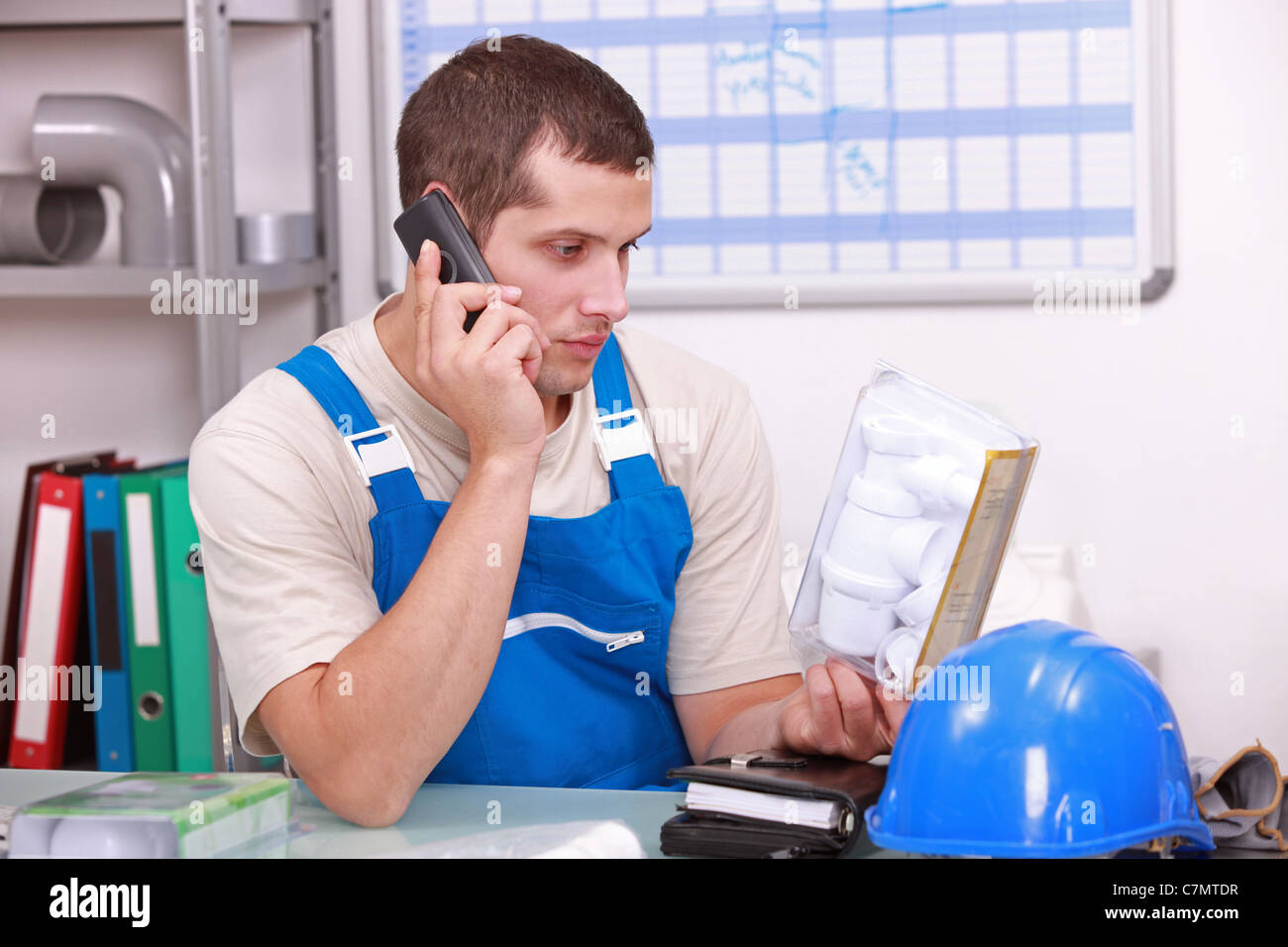 Plumber checking a part on the telephone Stock Photo - Alamy