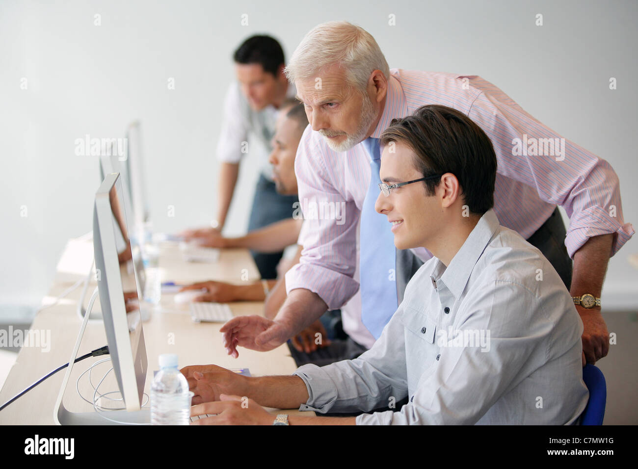 Manager in discussion with a younger worker using a computer Stock ...