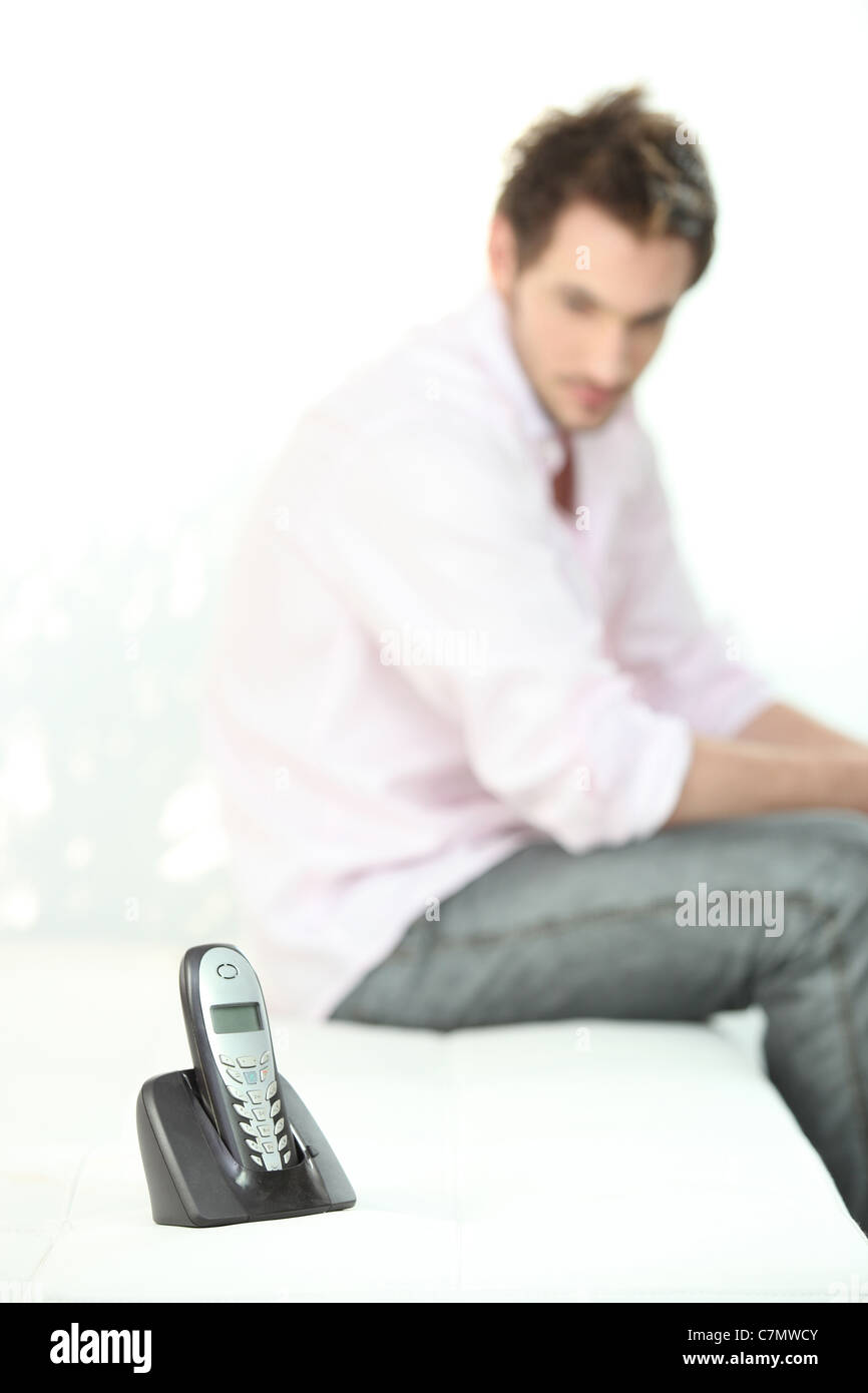 Young man waiting for the phone to ring Stock Photo - Alamy