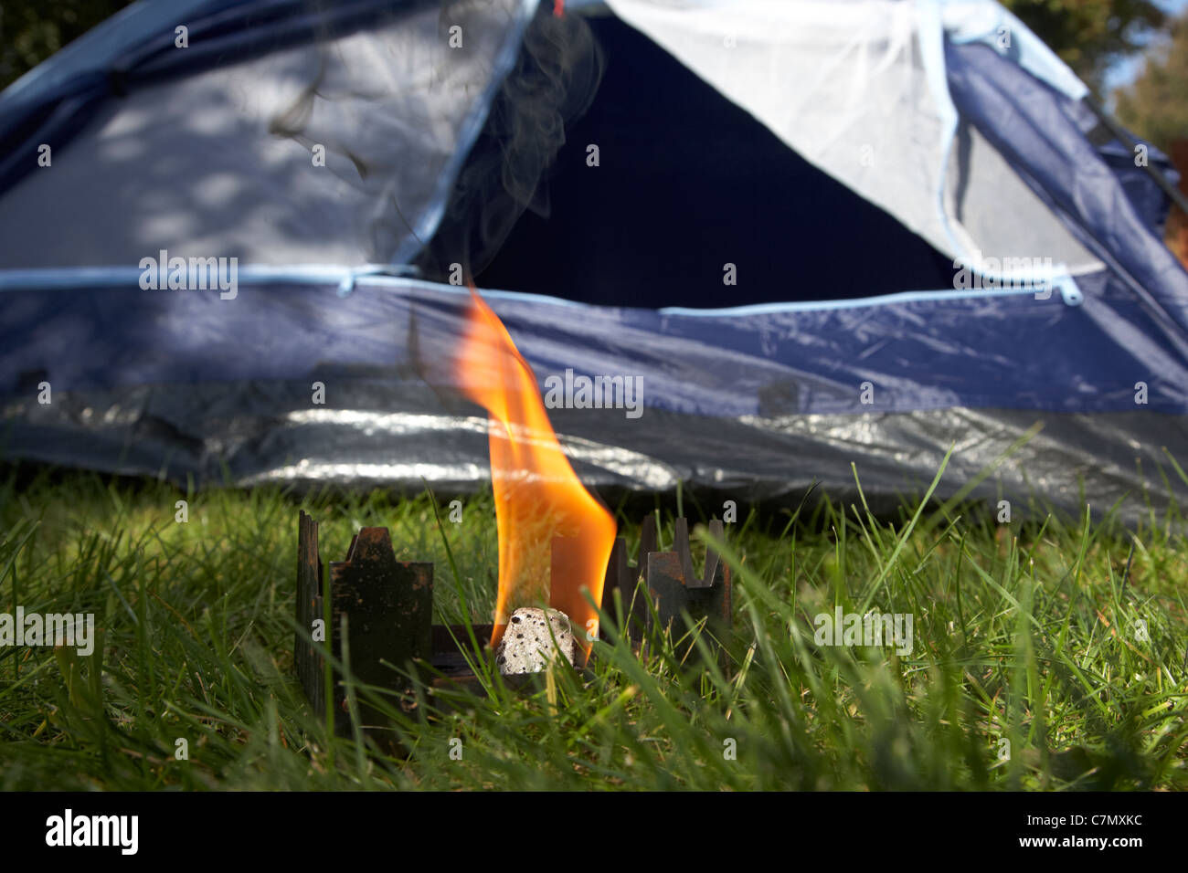 small solid fuel stove burning in front of the open door of a tent ...
