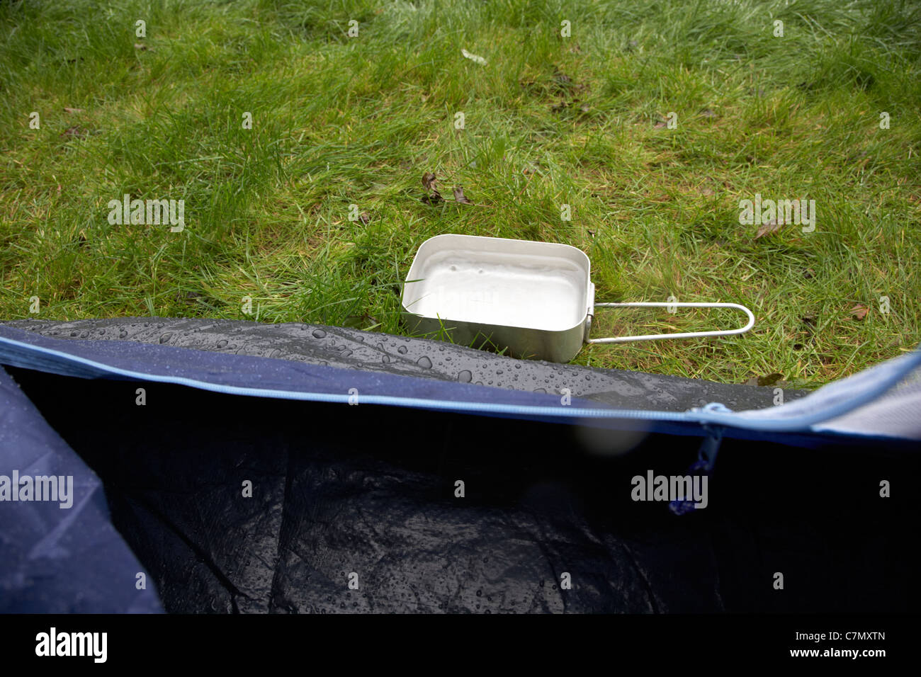 rain falling through the front door of an open tent with a container of ...