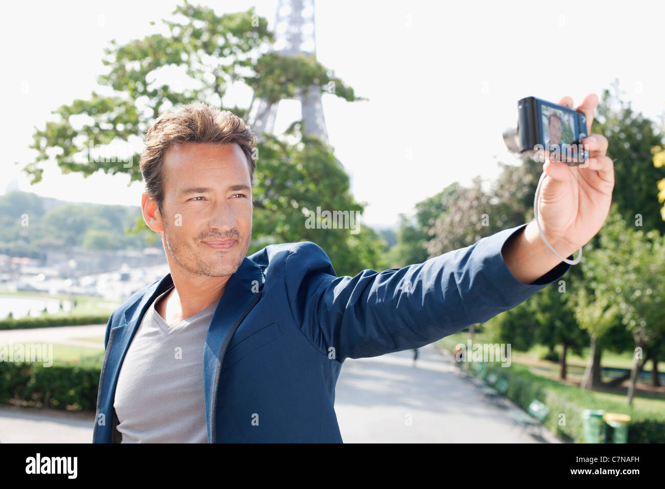Man taking a picture of himself with a digital camera with the Eiffel ...
