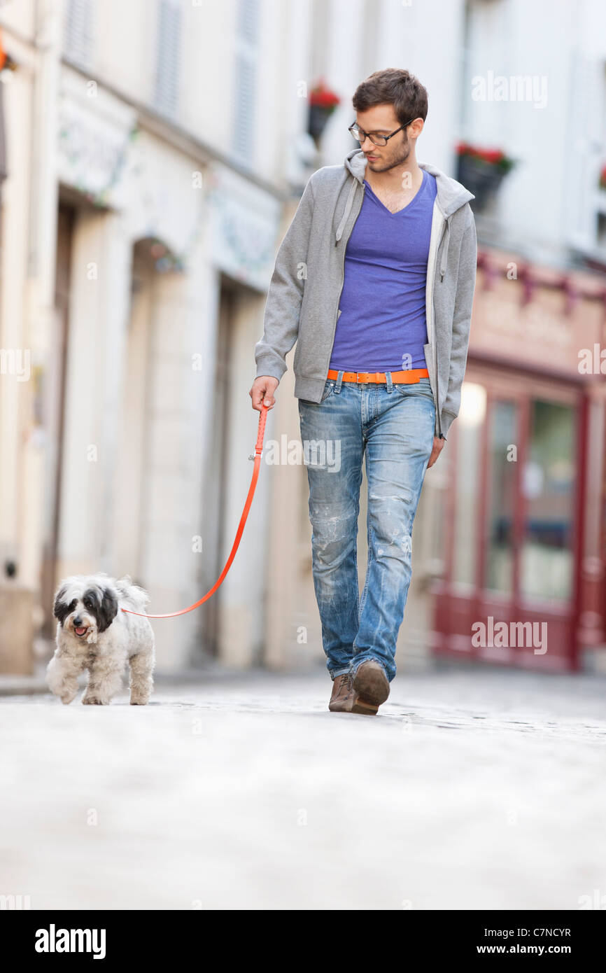 Man holding a dog on leash walking on the street, Paris, Ile-de-France ...