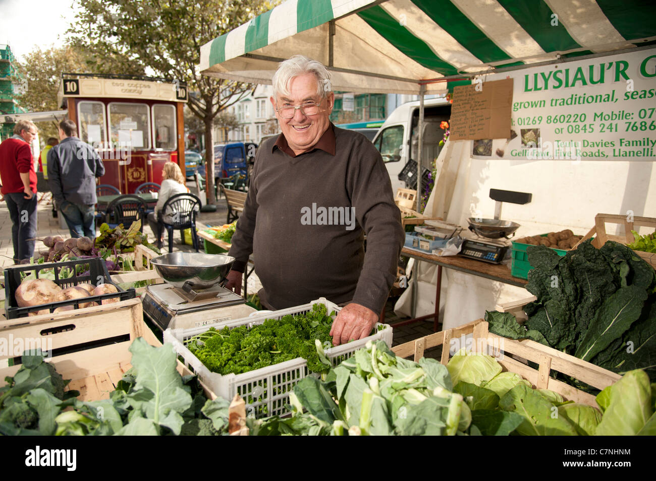 A smiling stallholder selling his locally produced vegetables at ...