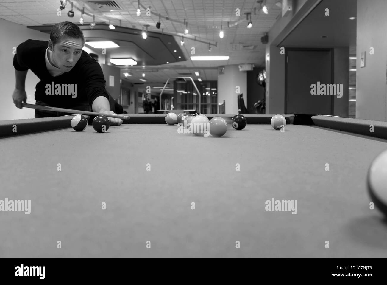 A young man shooting pool with motion blur on the pool balls. Shallow ...