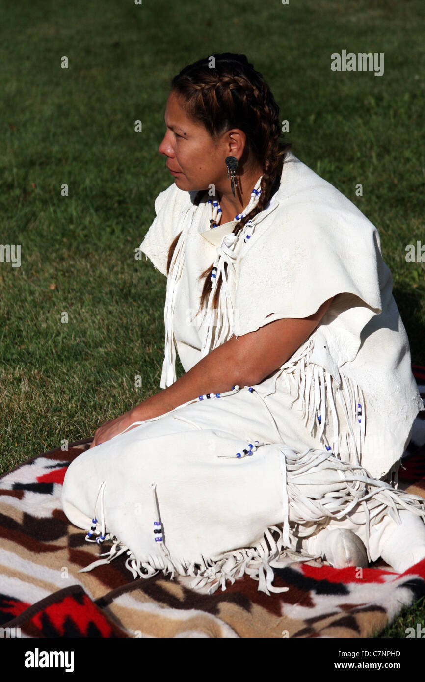 Native American Indian woman sitting on a blanket adjusting her leather ...
