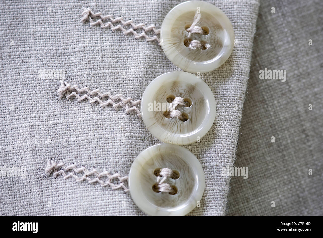 Buttons stitched onto the sleeve of a pale fabric jacket forming an ...