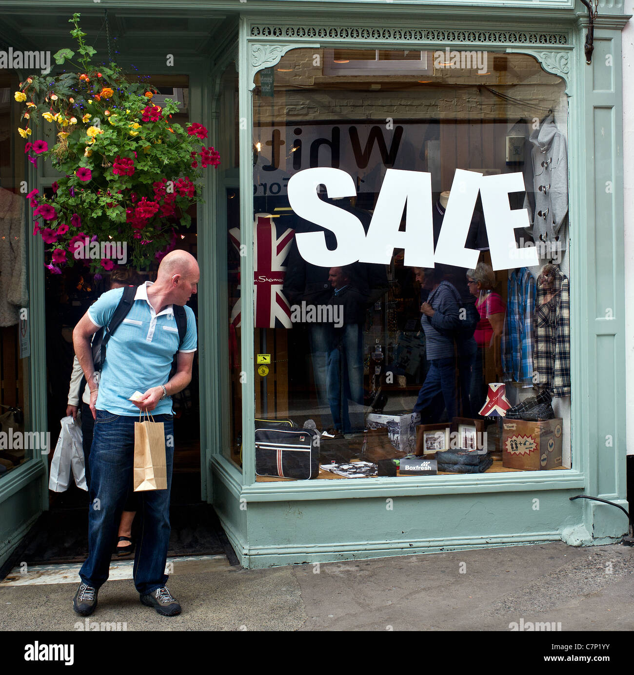A shopper looking in a shop window with a large sale sign Stock Photo ...