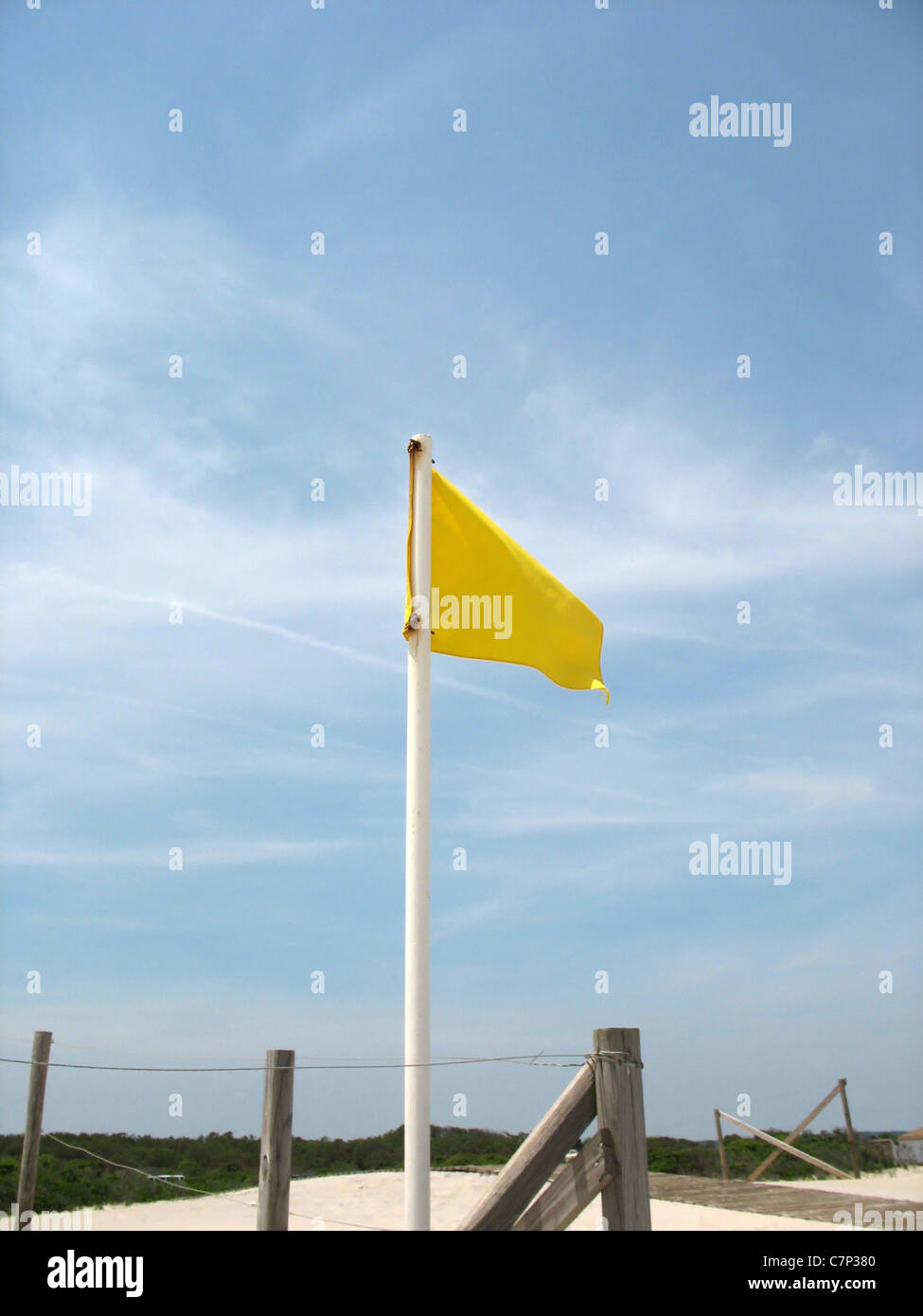 A yellow caution flag posted in the sand at the beach Stock Photo - Alamy