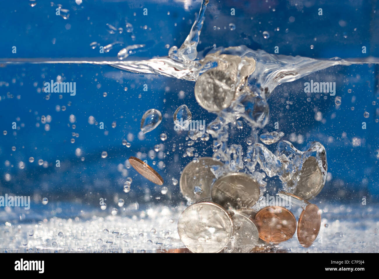 A handful of coins dropping into a pool of water Stock Photo - Alamy