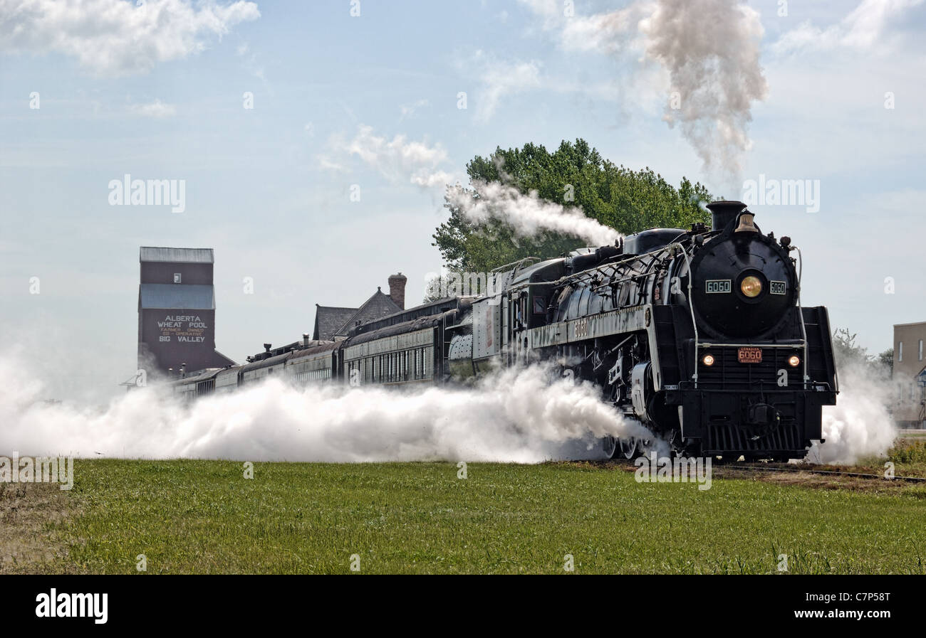 An antique steam locomotive and train cars leaving a station in Big ...